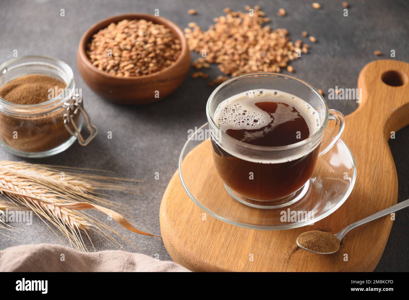 Barley coffee in glass cup, beans and ears of barley on brown ...