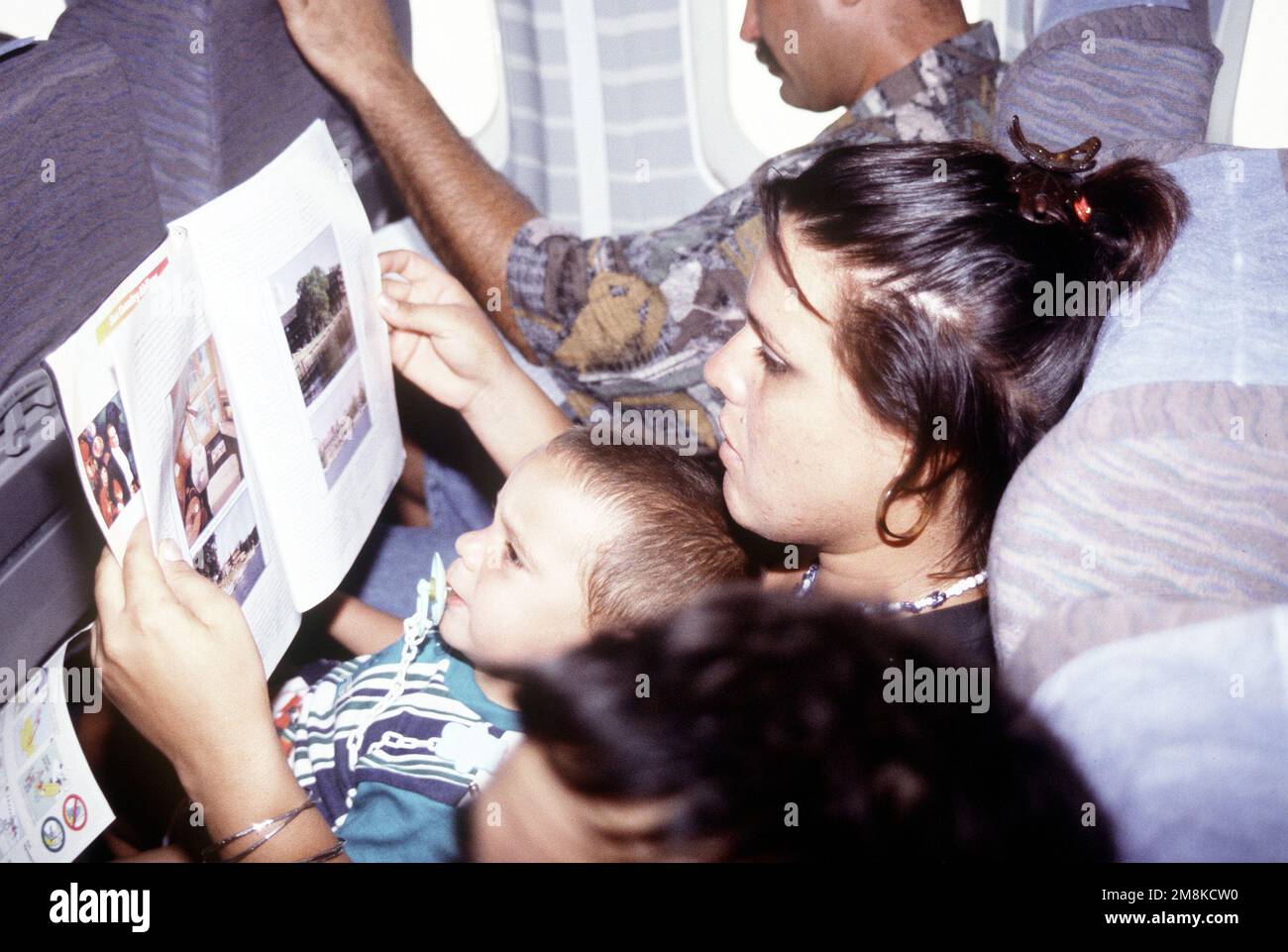 A cuban immigrant and her child look at an in-flight magazine as they ...