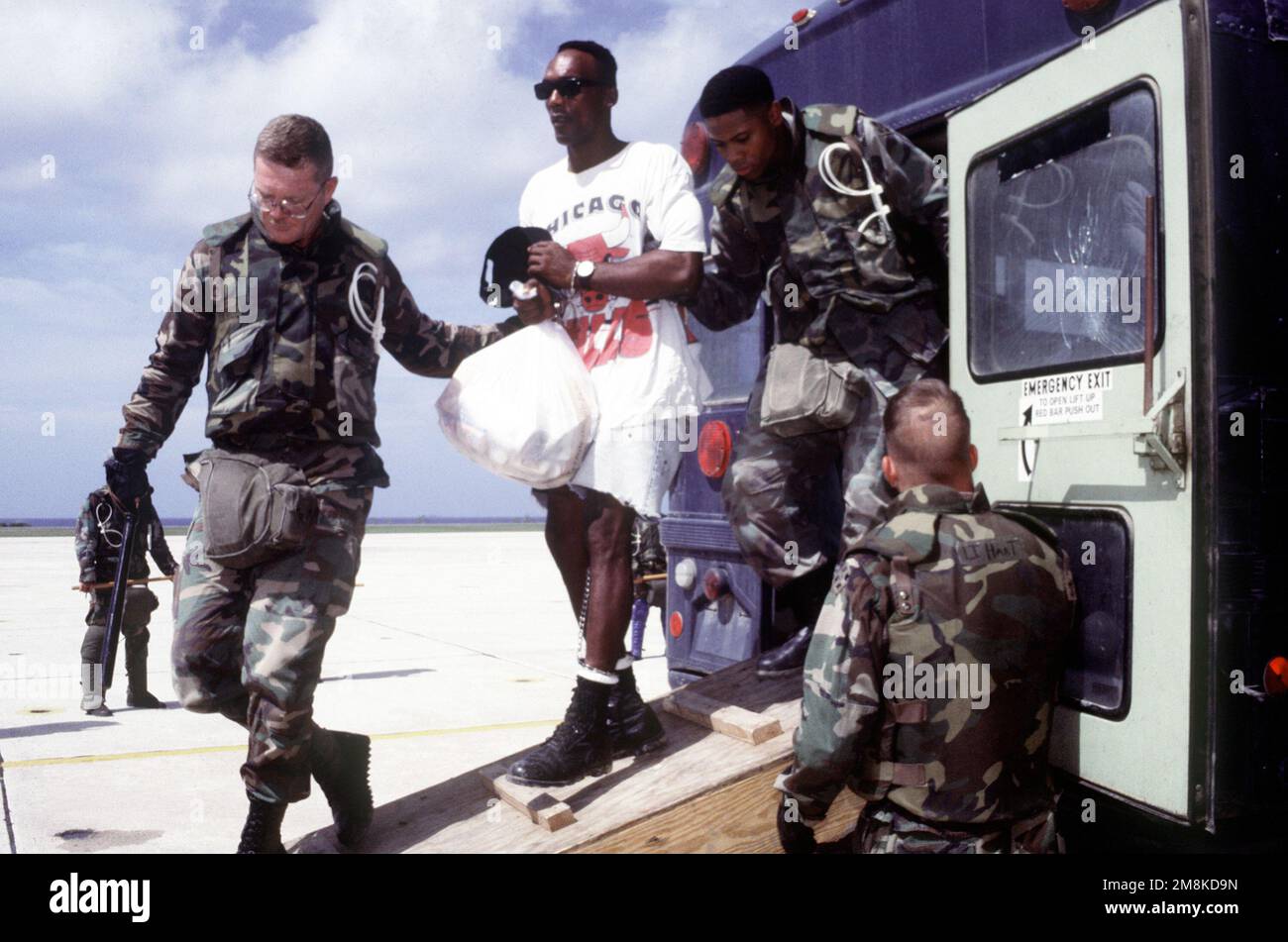 A Cuban immigrant is led off a bus by security personnel at US Naval ...