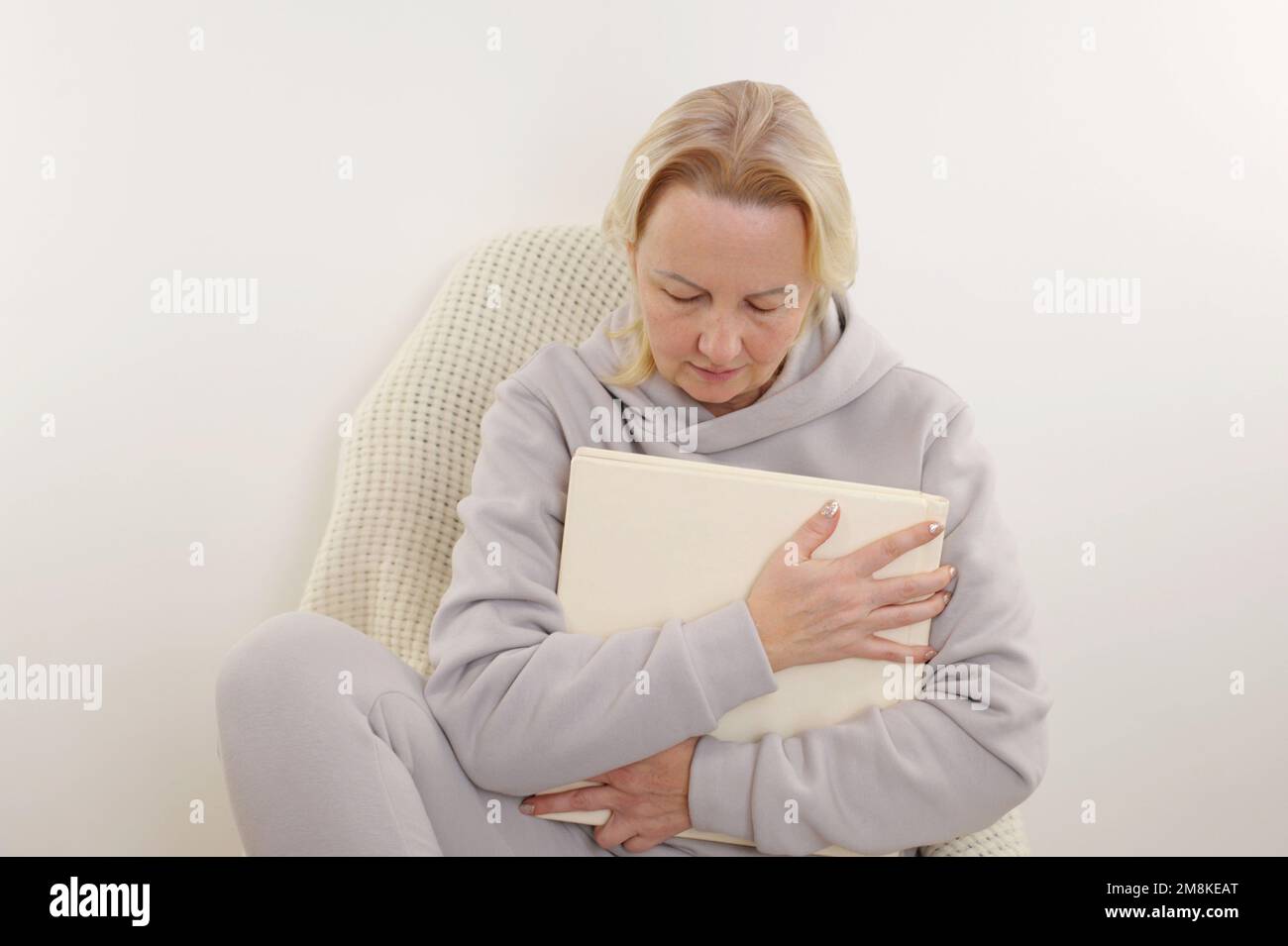 Woman hugging album dreaming remembering something in light-colored ...