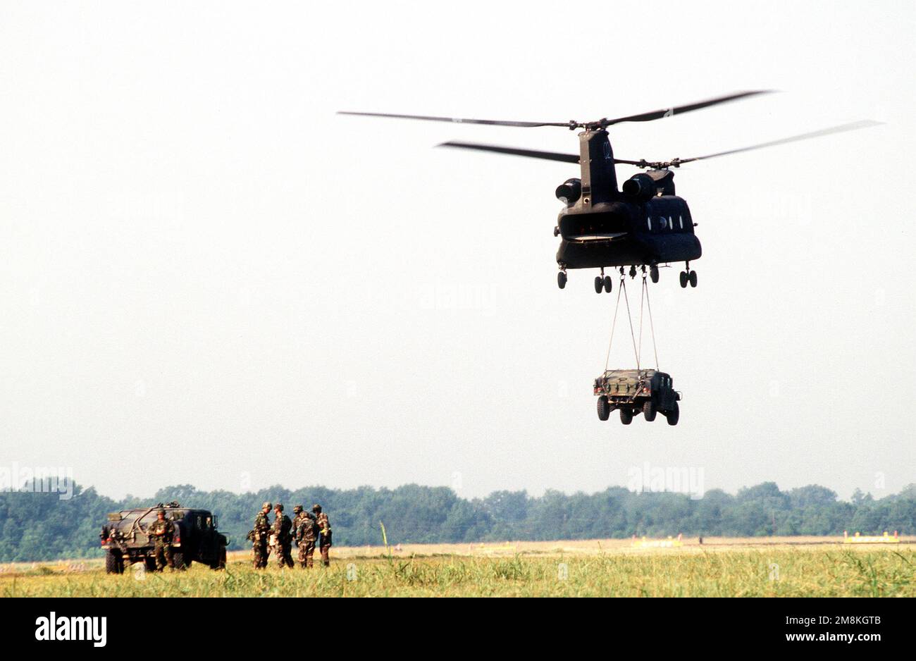 A US Army CH-47 Chinook helicopter sling loads a High-Mobility Multipurpose Wheeled Vehicle ...
