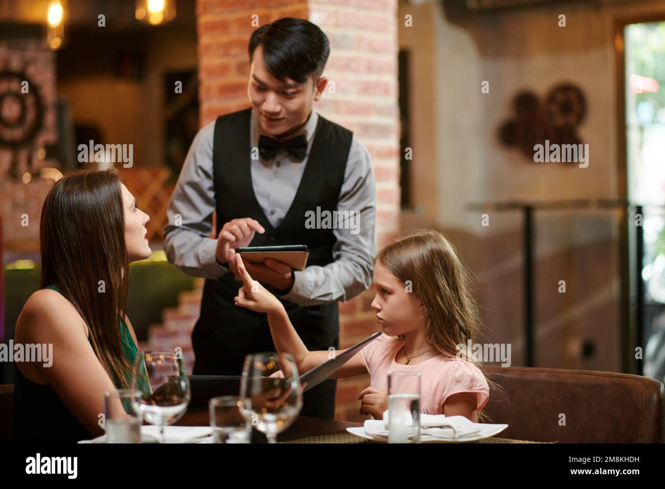 Fancy restaurant waiter taking order from mother and daughter Stock Photo - Alamy