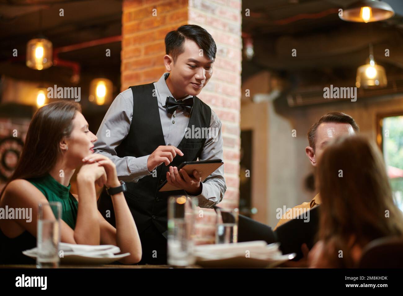 Smiling restaurant waiter taking order from family Stock Photo - Alamy