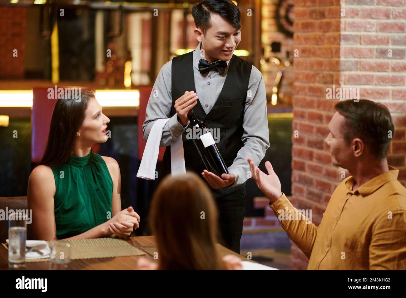 Fancy restaurant owner offering good wine to family Stock Photo - Alamy