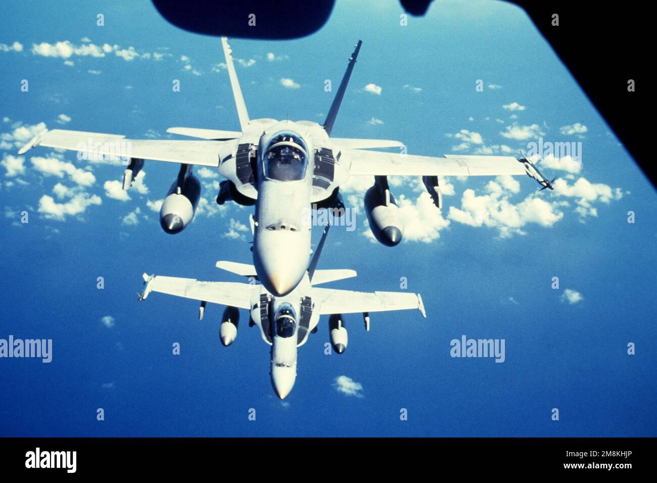An overhead aerial view of two US Navy F/A-18 Hornets (one beneath the ...