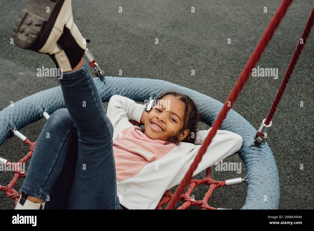 A happy little girl lying on a swing in a playground Stock Photo - Alamy
