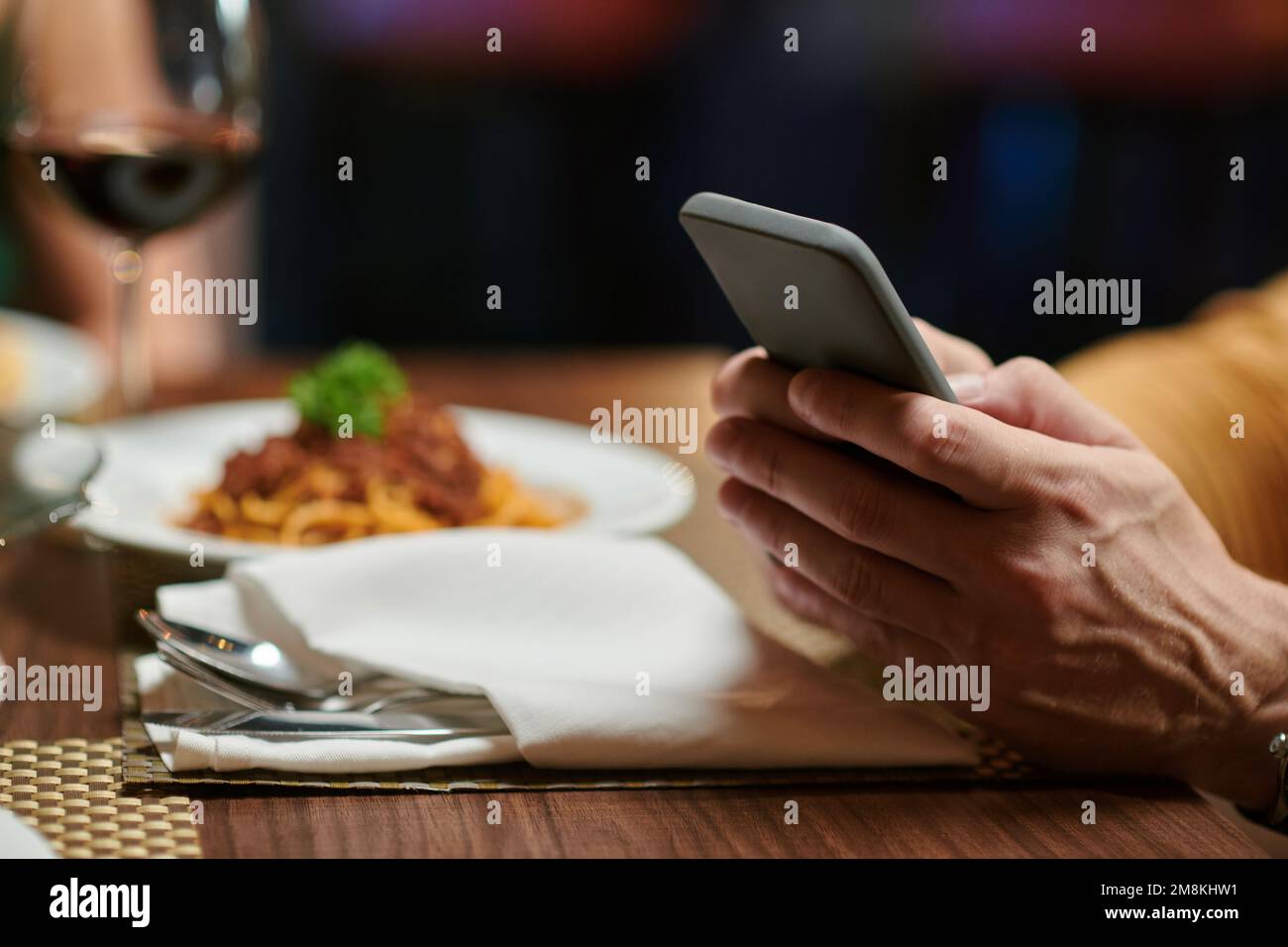 Closeup image of man checking mobile application when eating dinner in ...