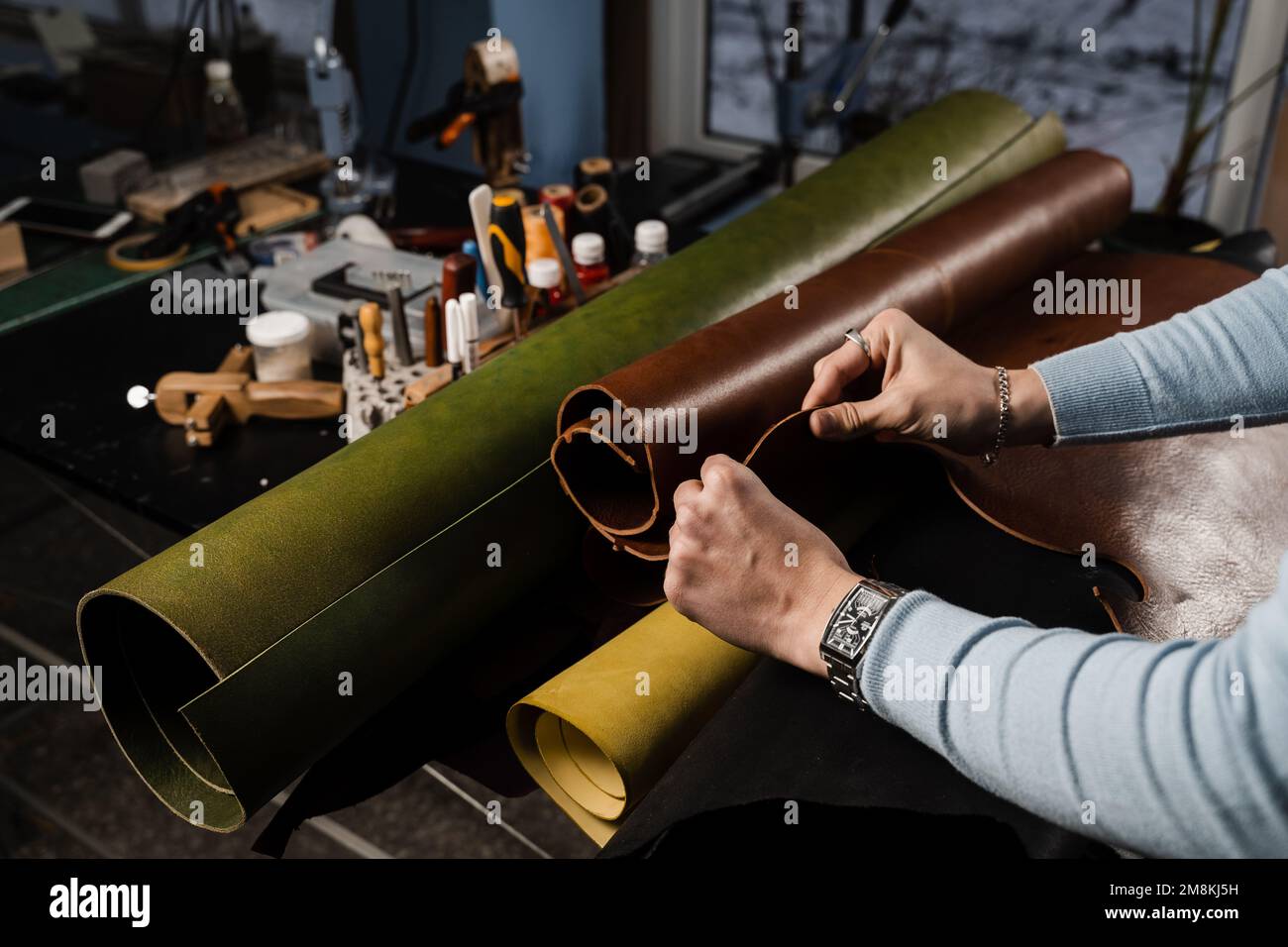Leather craftsman touches roll of genuine leather in workshop. Handmade ...