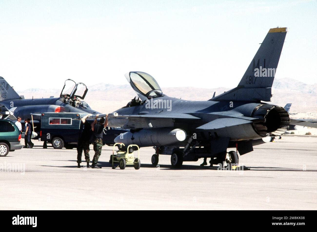Two ground crew personnel install an air combat range data link pod on ...
