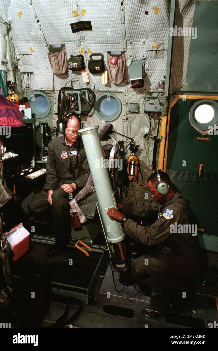 US Air Force MASTER Sergeant Robert Perry loads a dropsonde sensor into ...