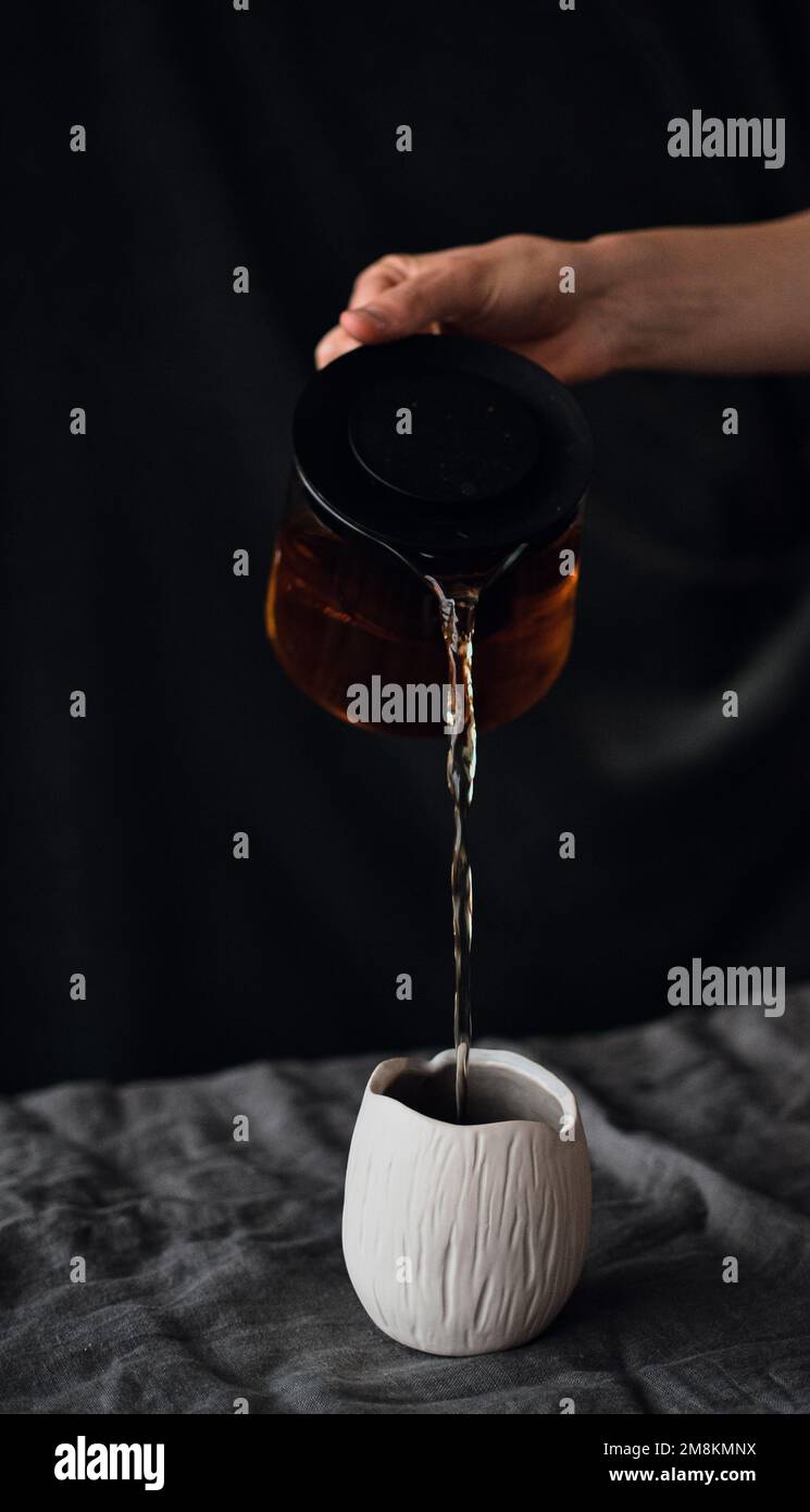pouring tea from a teapot into an earthenware mug Stock Photo - Alamy