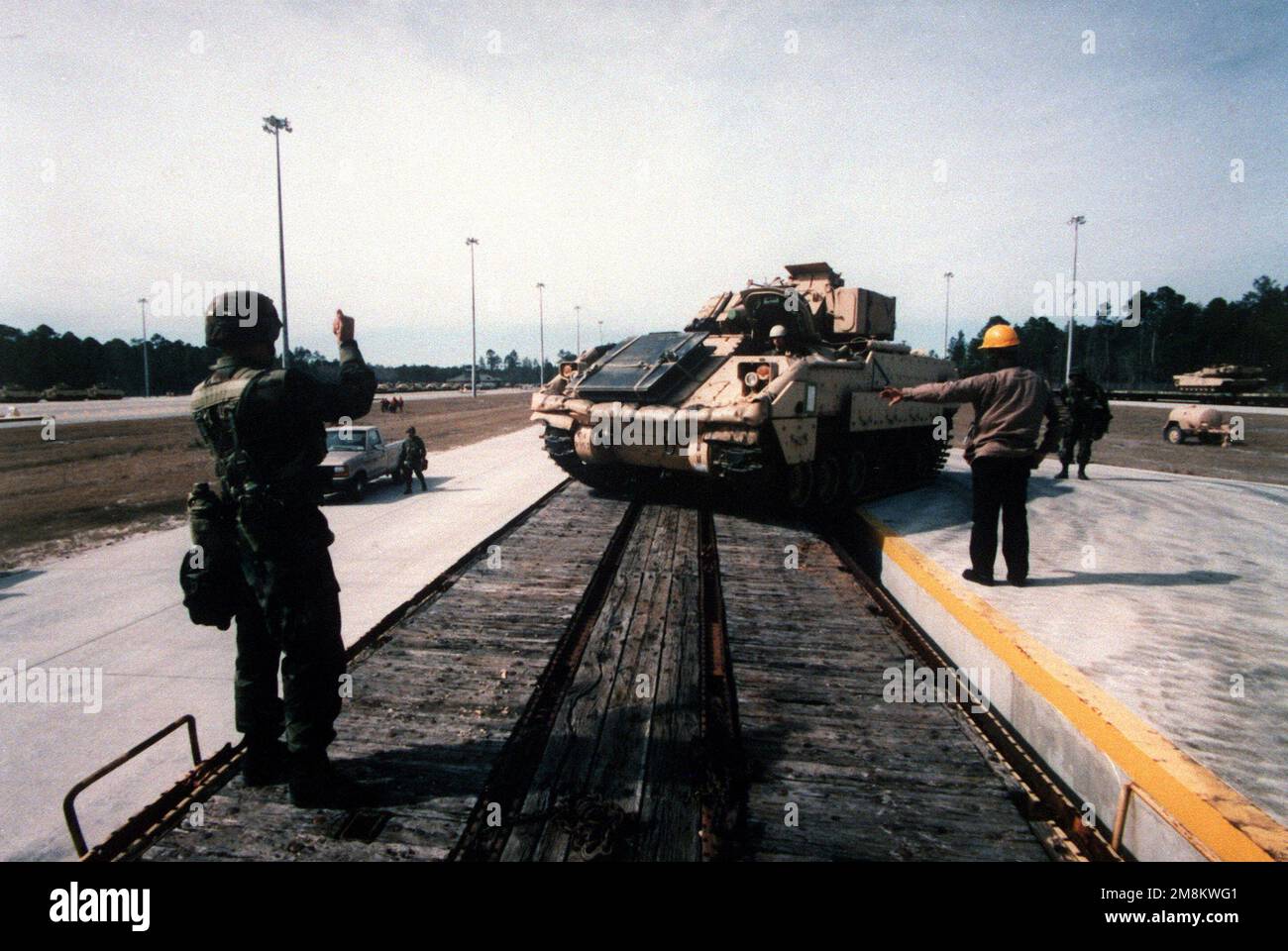 An M-2 Bradley is driven onto the rail at the marshaling area during ...