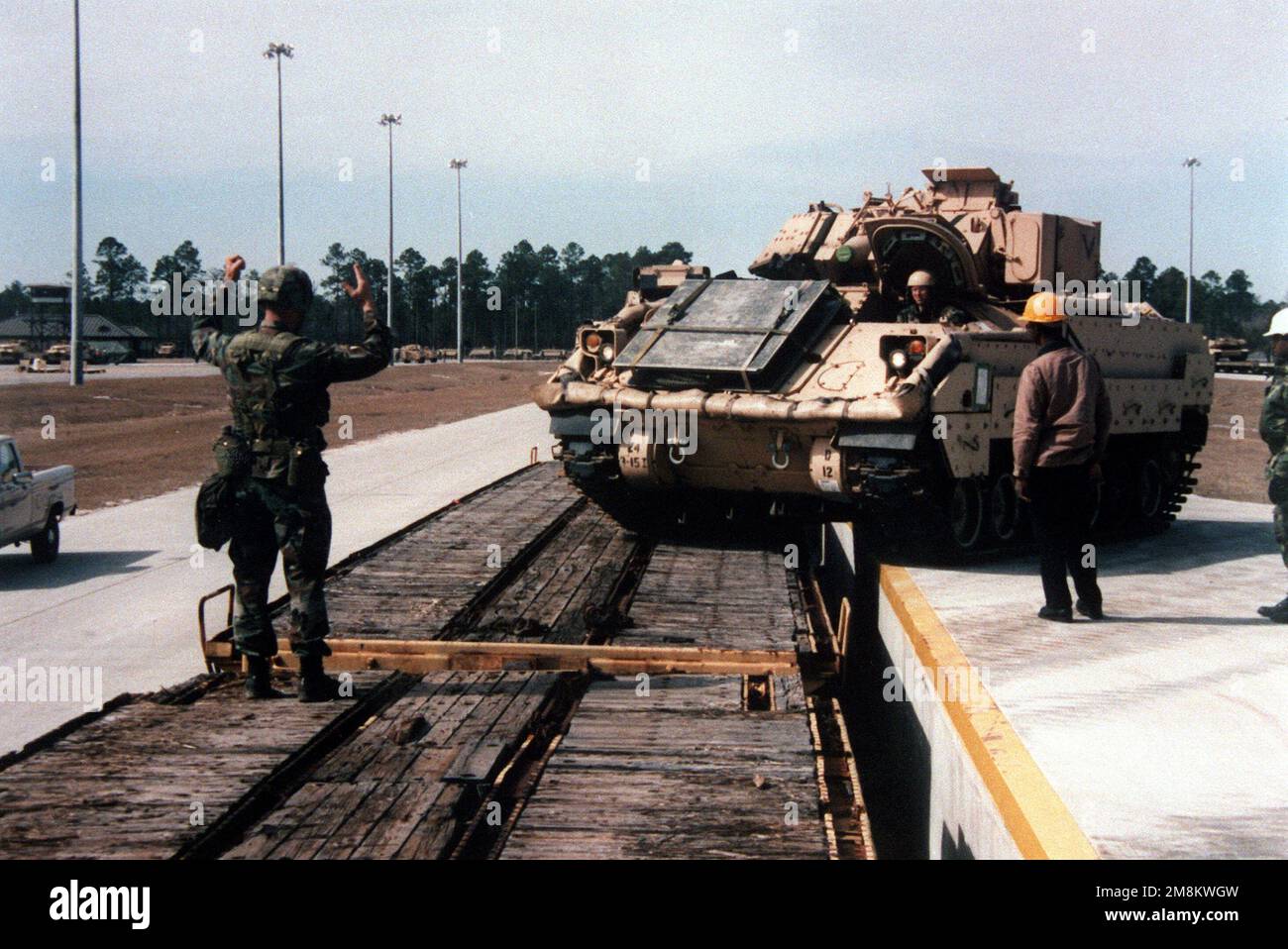 An M-2 Bradley is driven onto the rail at the marshaling area during ...