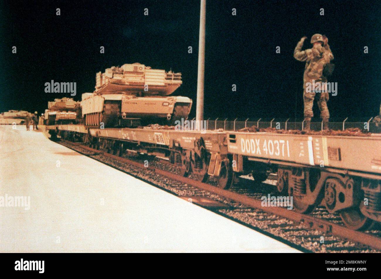 A soldier guides an M-1 Abrams Tanks on flatbed railcars at the well ...