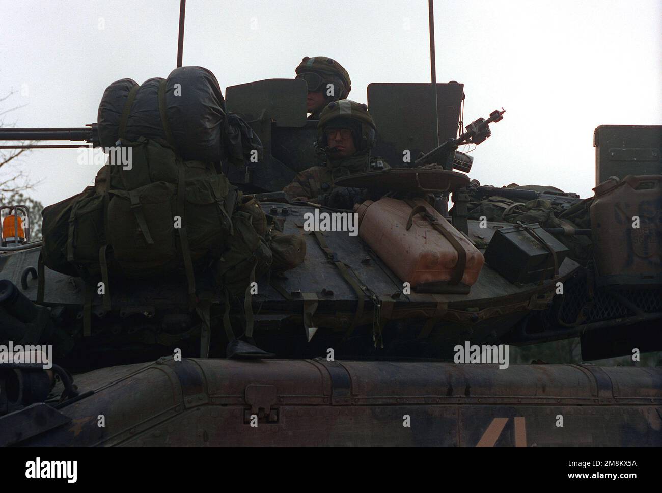 Close up view of the turret of a tank as soldiers keep a watchful eye ...