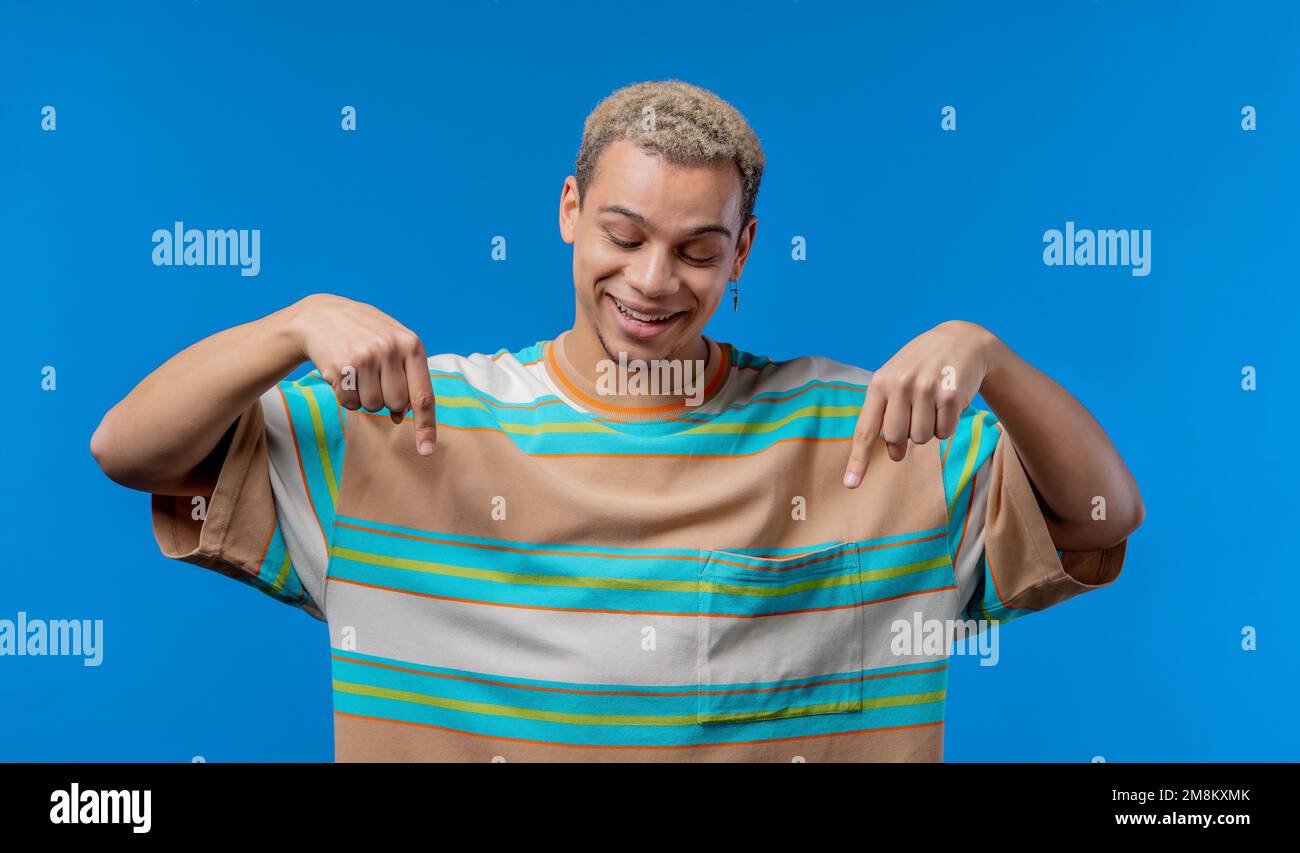 Happy man pointing down to advertising area. Blue background. Young guy ...