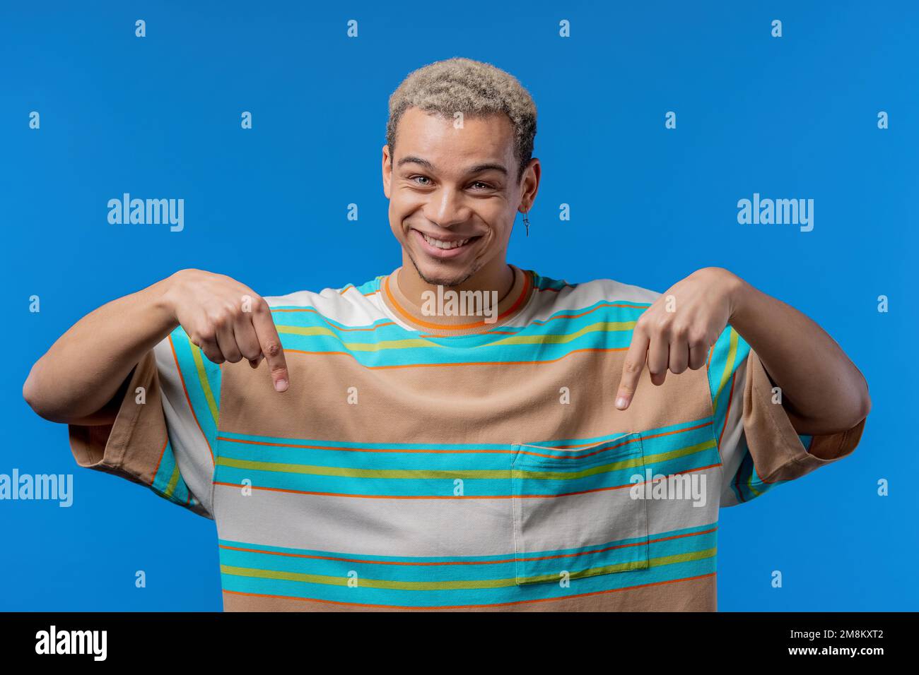 Happy man pointing down to advertising area. Blue background. Young guy ...