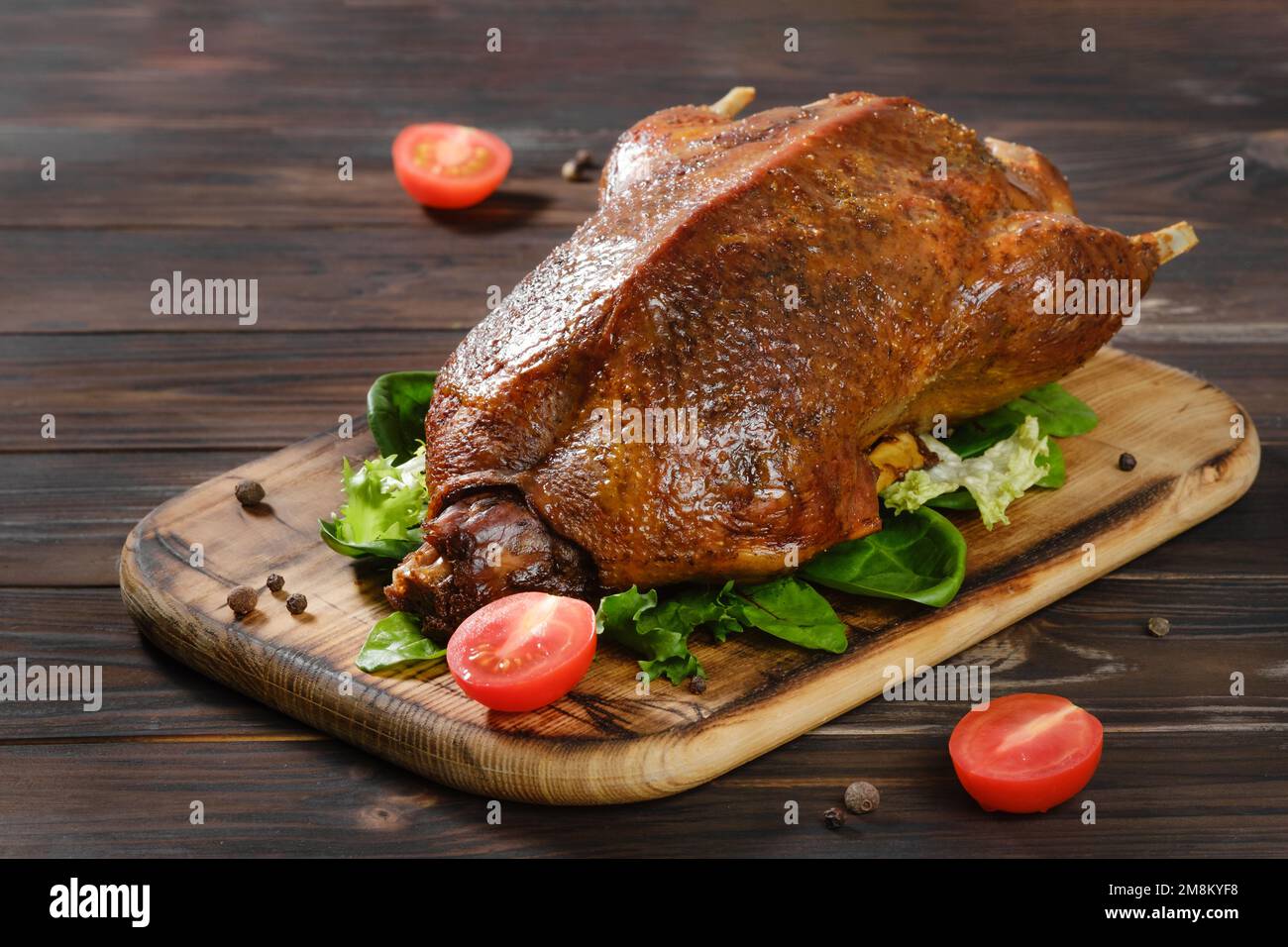 Whole roast duck and vegetables on a dark wooden board. horizontal view ...
