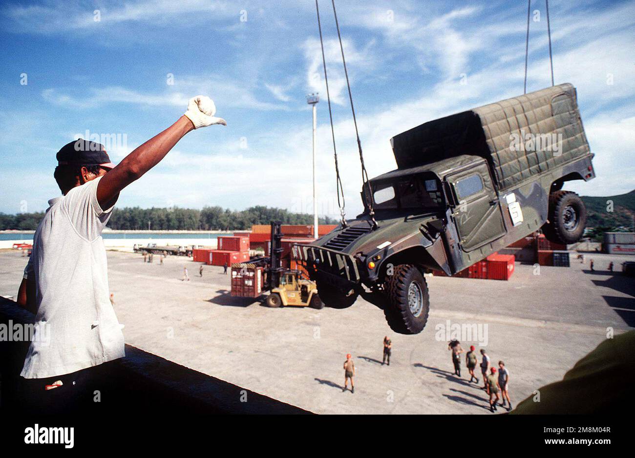 A Thai stevadore directs the off load of US military High-Mobility ...