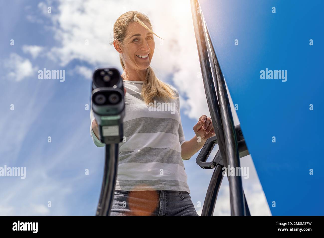 Happy woman holding a DC CCS2 EV charging plug connector on ...