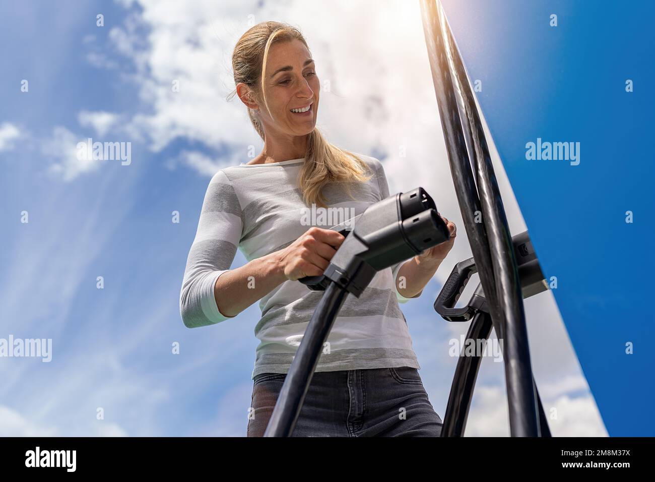 Happy woman insert a DC CCS2 EV charging plug connector to a ...