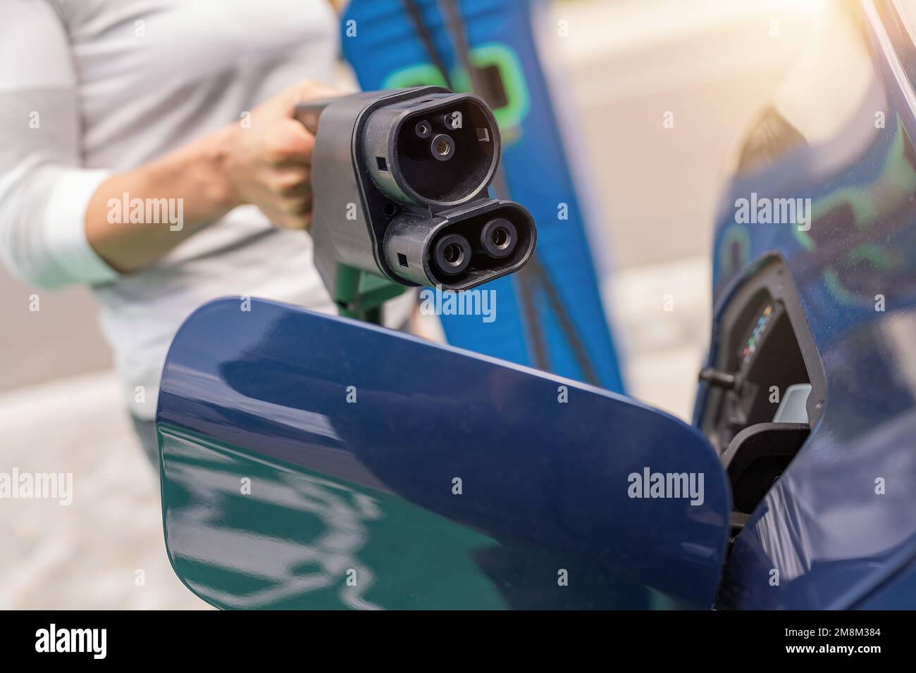 Woman inserting a DC CCS2 EV charging connector into electric car ...