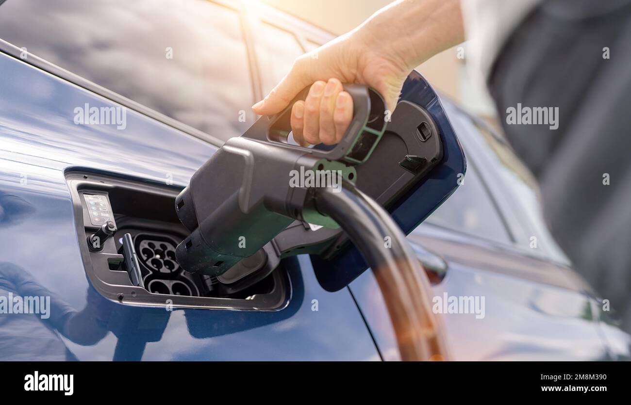 Woman inserting a DC CCS2 EV charging connector into electric car ...