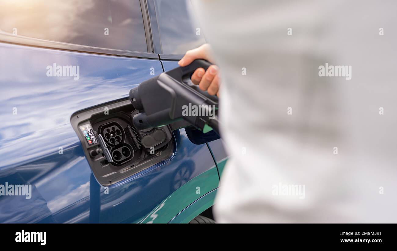 Woman inserting a DC CCS2 EV charging connector into electric car ...