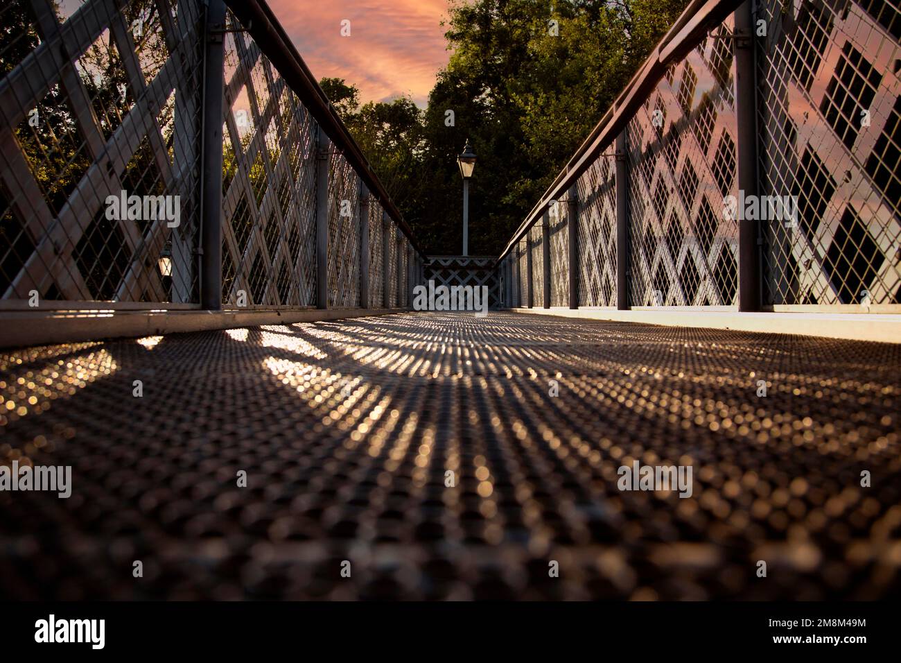 Low angle view of a steel metal footbridge, with mesh railings, in late ...