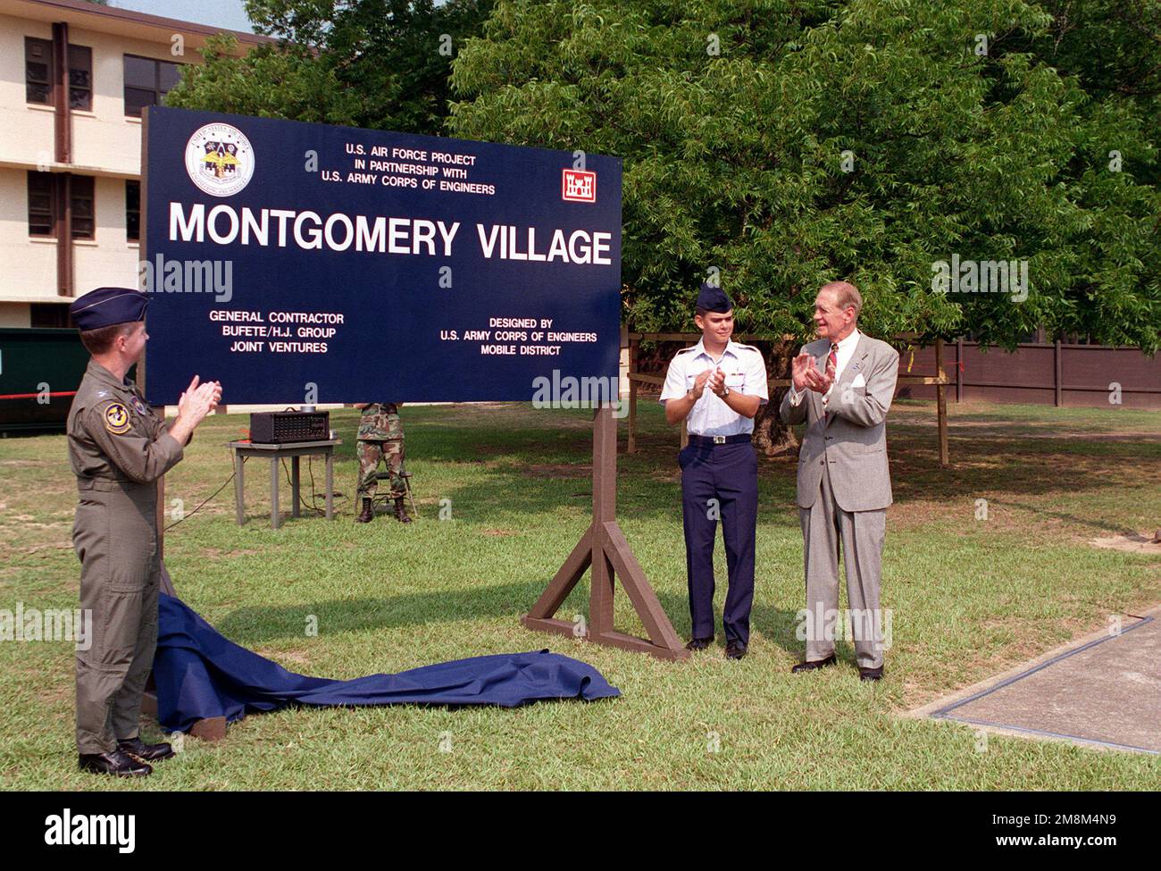 Congressman Montgomery and two Air Force officers applaud as the sign ...