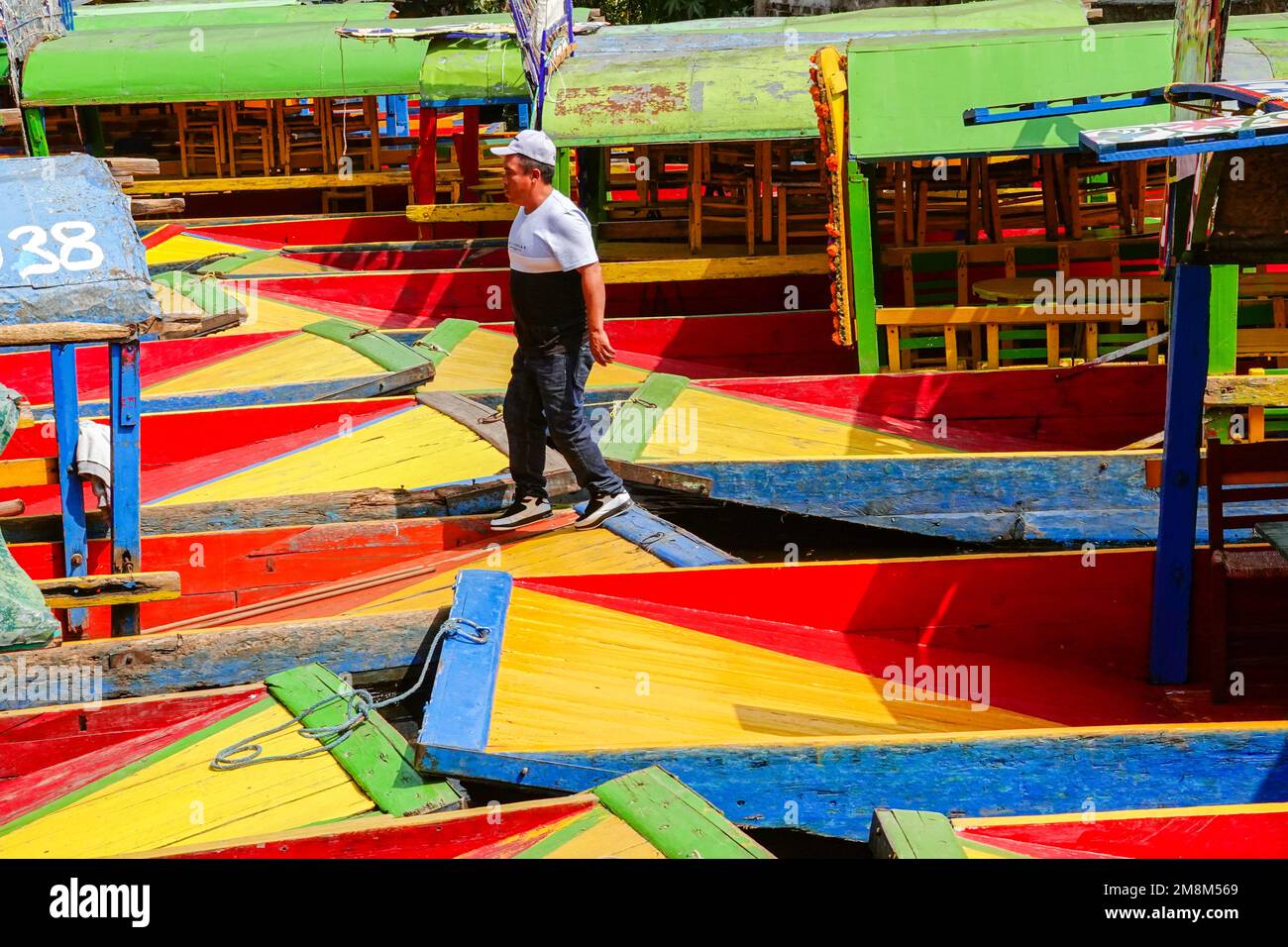 A boat owner walks across the colorful painted decks of rajinera boats ...