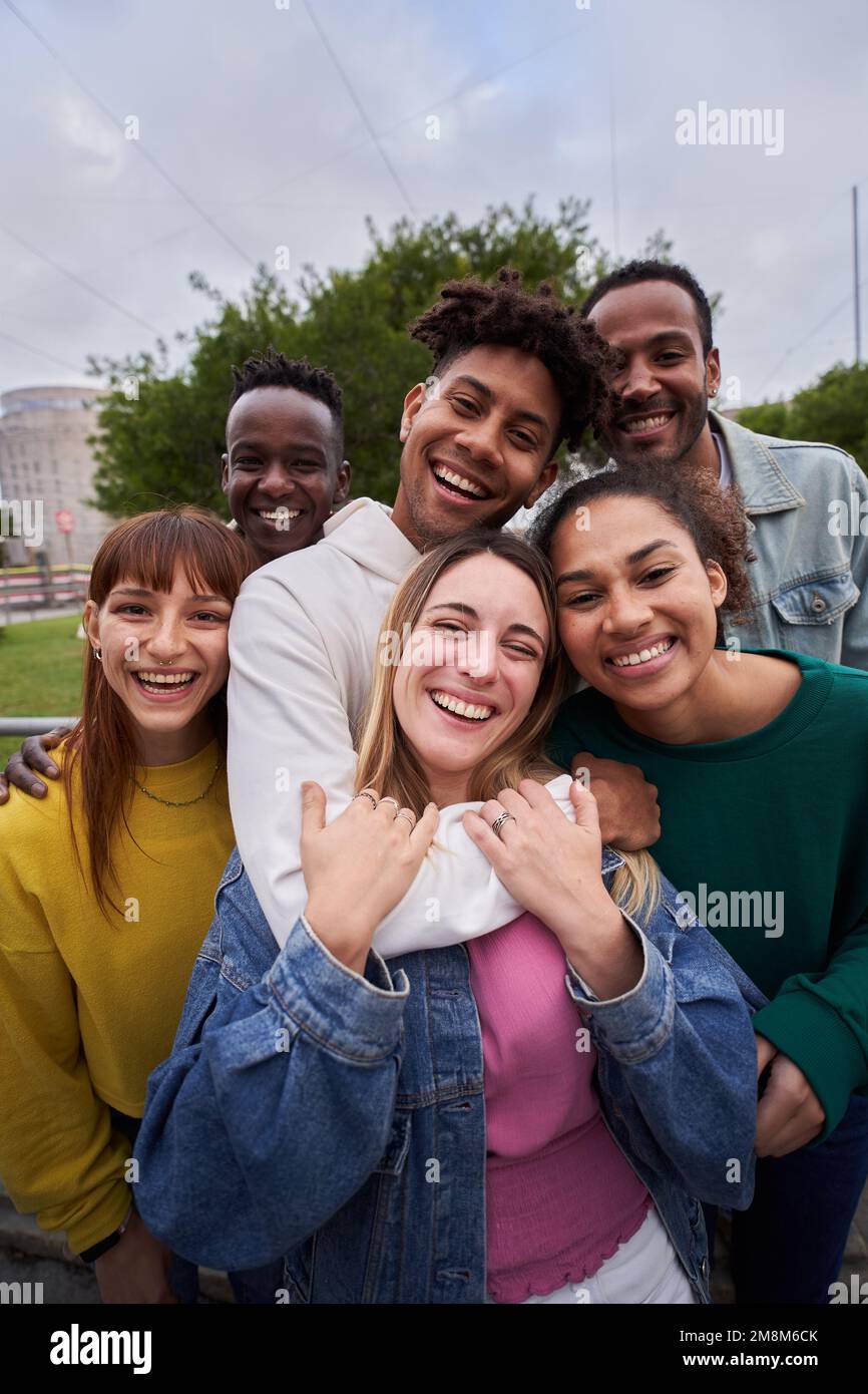 Vertical. Young people embrace looking at the camera outside. Smiling ...