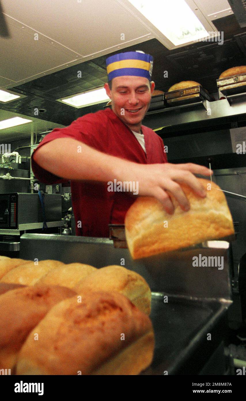 A US Navy Mess Management SPECIALIST 3rd Class removes bread from the ...