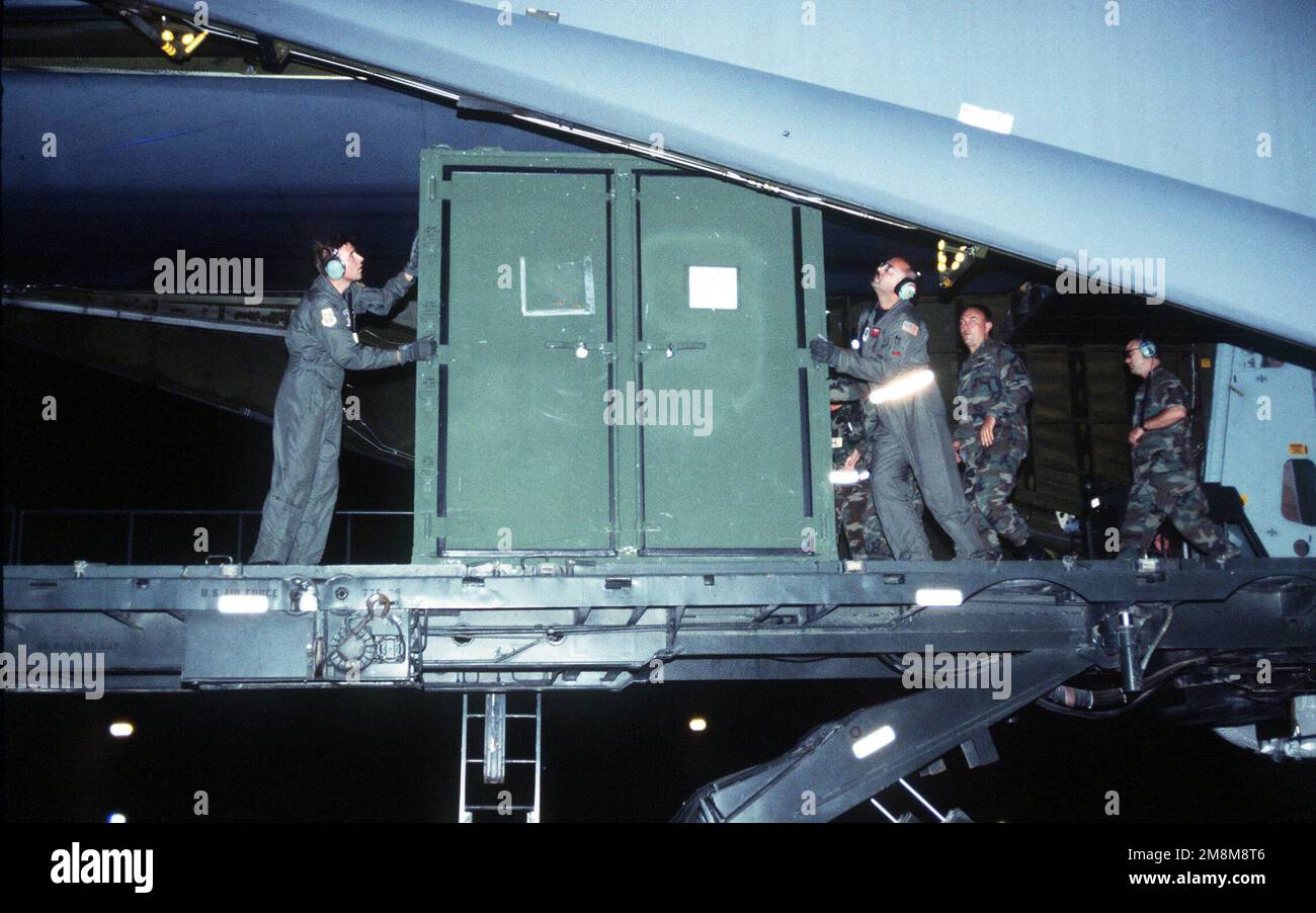 Aircraft crew members unload cargo to make room for equipment to be ...
