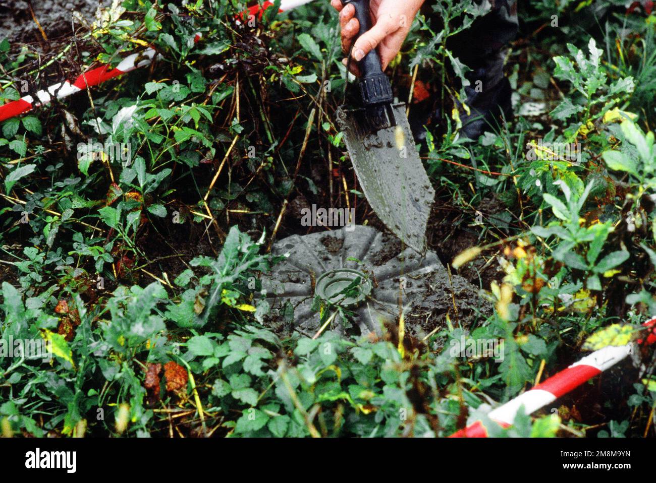 An inert land mine is buried and camouflaged in training lanes. The ...