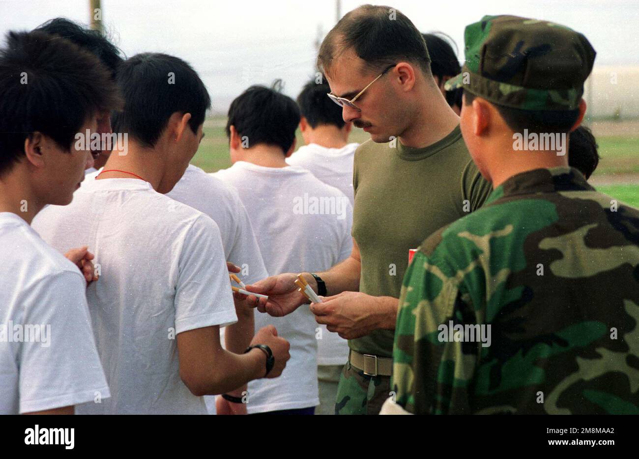 A US Army joint task group (JTG) member hands out cigarettes to each ...