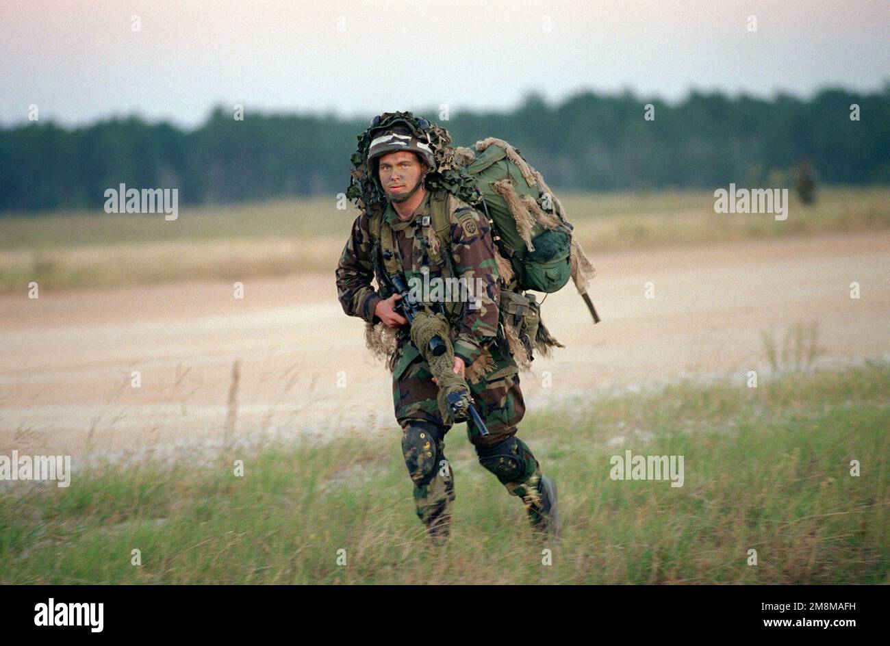 After a successful landing, a paratrooper dressed in camouflaged ...