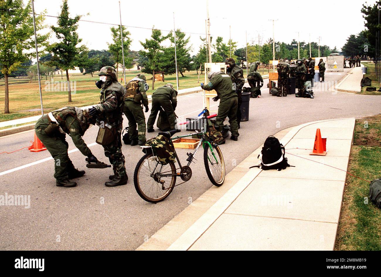 Airmen wearing chemical warfare gear processes through a ...