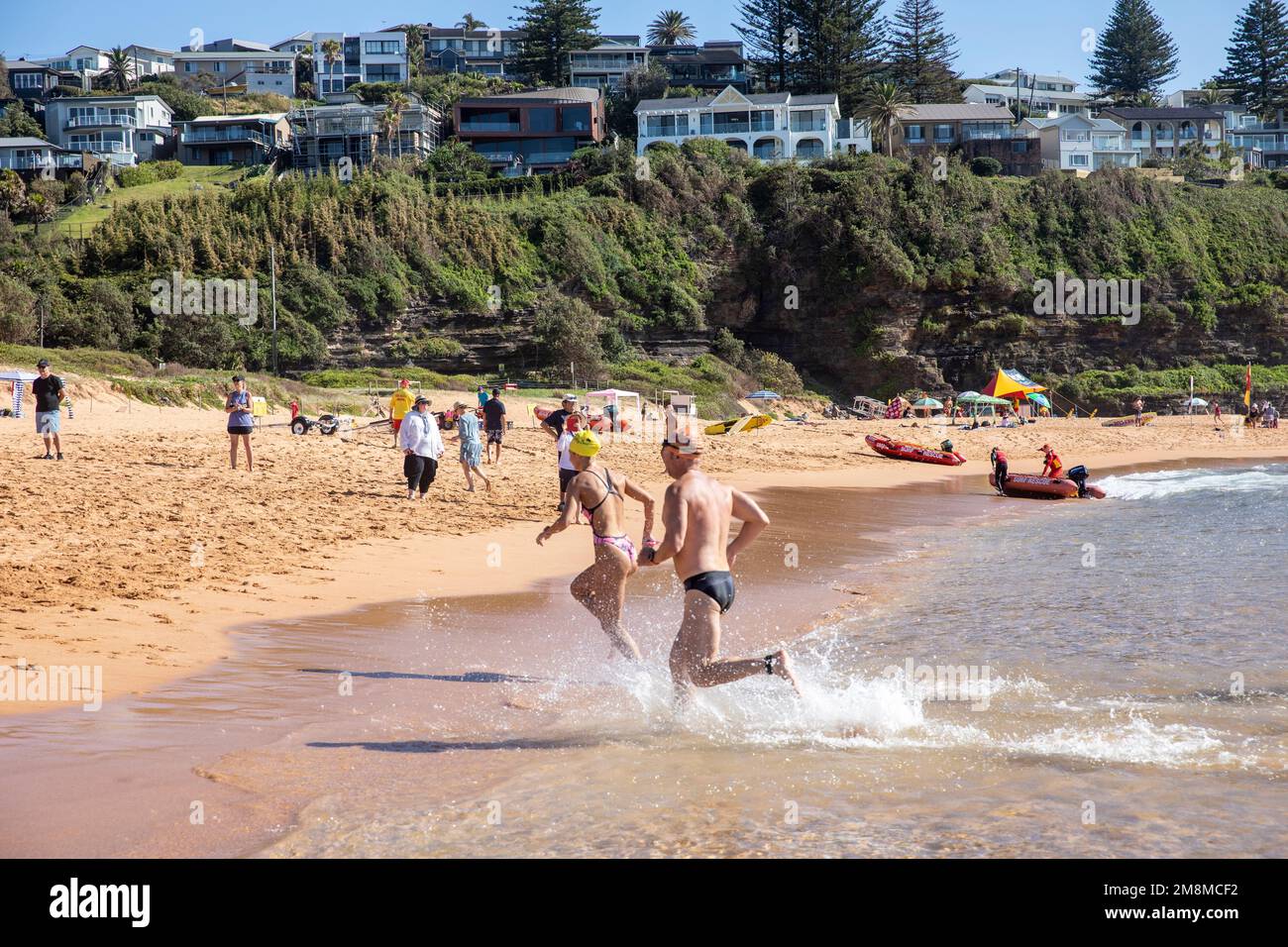 Ocean surf swim race at Bilgola Beach Sydney, male and female swimmers sprint out of the ocean ...