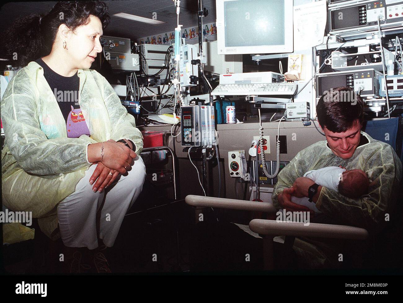 A civilian nurse supervises as a young Navy man meets his new child for ...