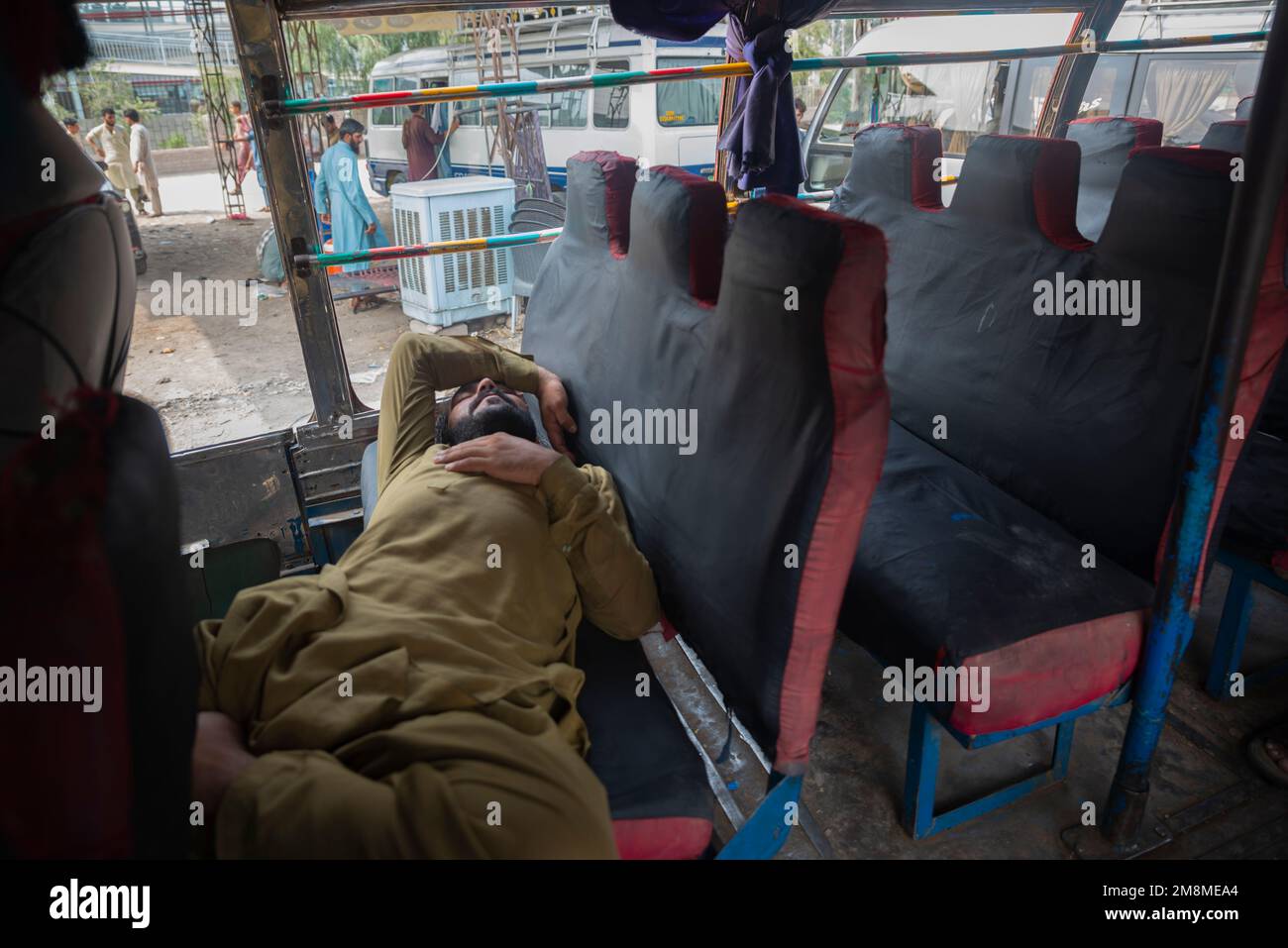 Driver sleeping on the seats of a colorfully painted bus, Peshawar ...