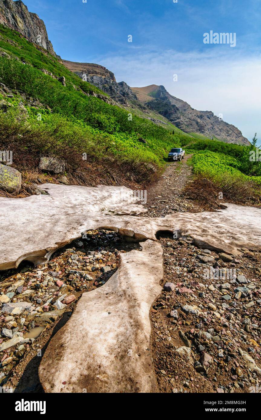A rough road high in the mountains is blocked by patches of unmelted ...
