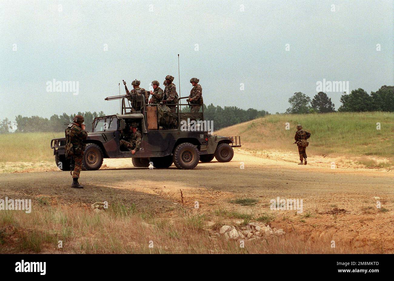 Soldiers on patrol stand on the rear of a High-Mobility Multipurpose ...