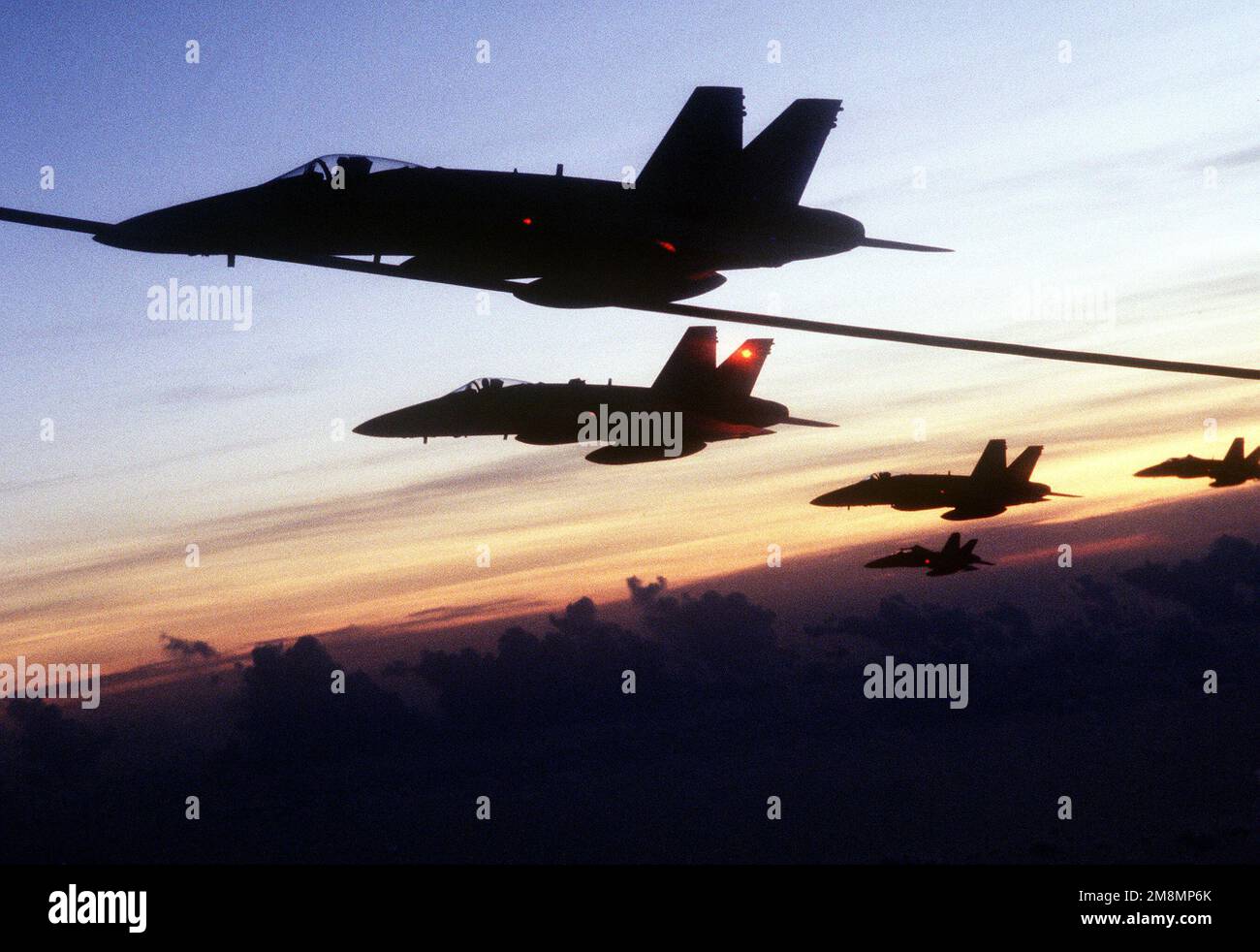 Five Navy F/A-18 Hornet aircraft, above the clouds at sunset, fly in ...