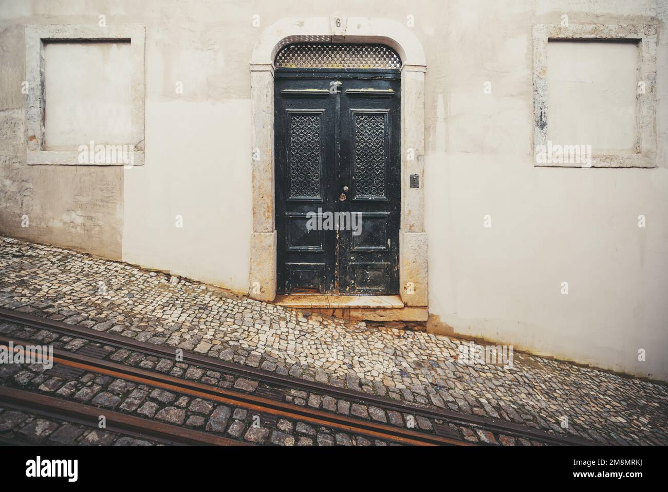 A black metal rusty door in a building with cemented windows, this worn ...