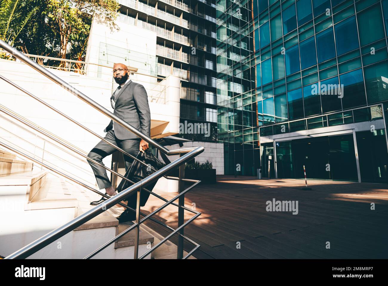 A black white-collar employee moving up the staircase, a metallic ...