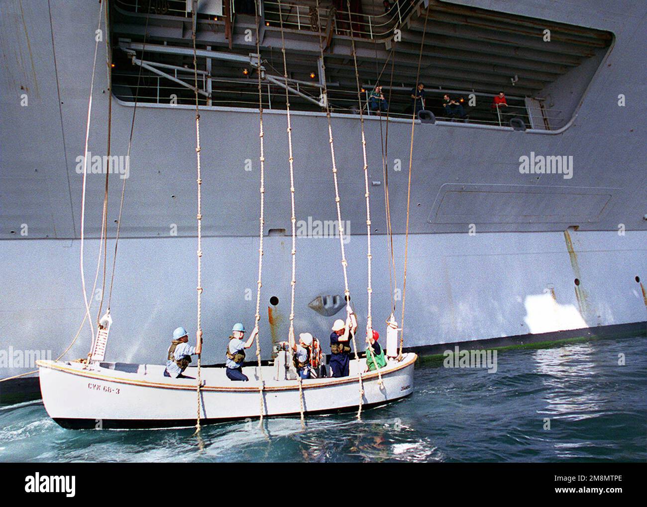 US Navy sailors prepare a motor whale boat for hoisting aboard the ...