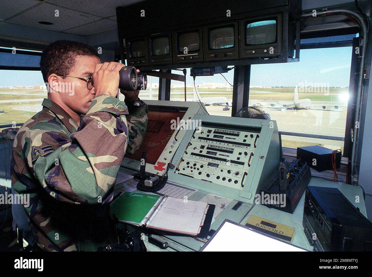 A1C Joseph Logan stands watch, looking through binoculars, over Navy E ...