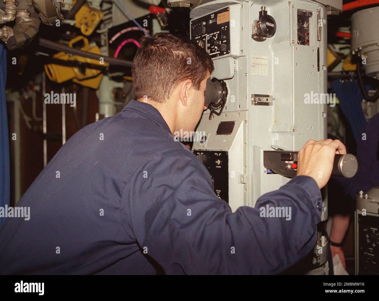 A crewmember of the Los Angeles class submarine peers through the ...