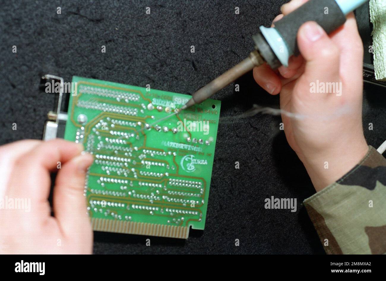 With a soldering iron, the skilled hands of a maintenance technician ...